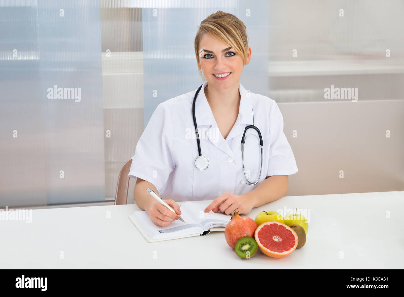 Cheerful female doctor writing hi-res stock photography and images - Alamy