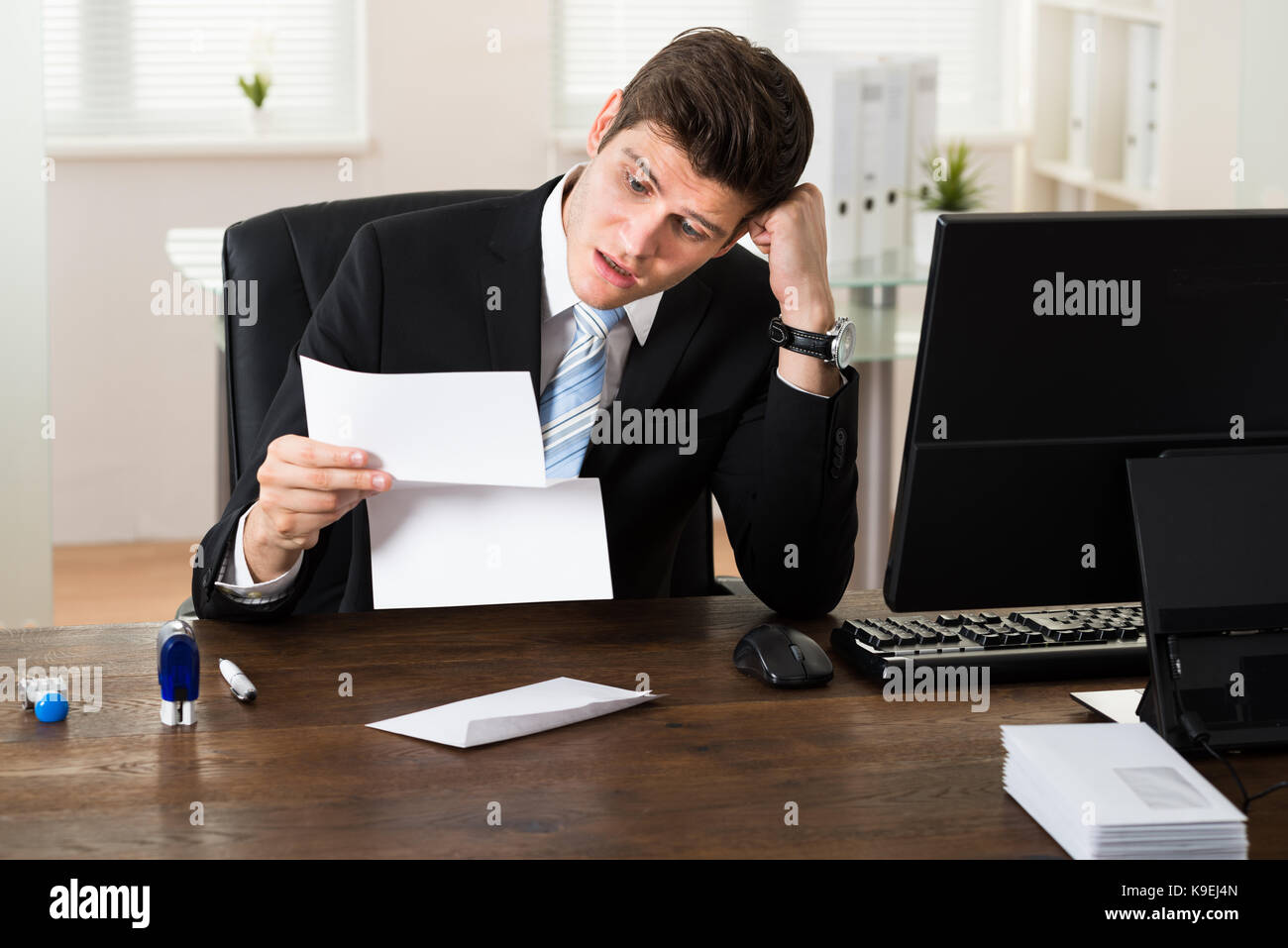 Portrait Of Young Shocked Businessman Looking At Document In Office ...