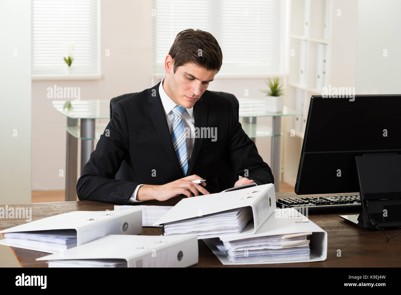Young Businessman At Desk Doing Accounting In Office Stock Photo - Alamy
