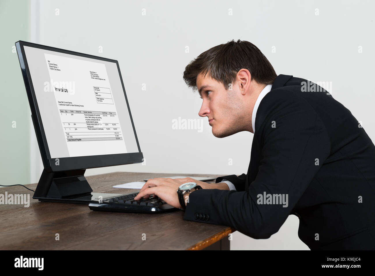 Young Businessman Looking At Invoice On Computer Screen In Office Stock ...