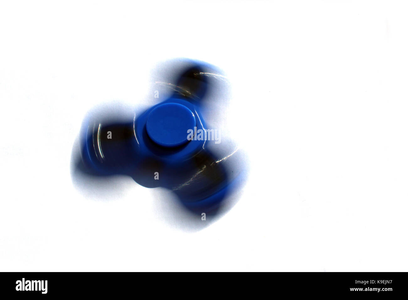 Blue plastic fidget spinner spinning on white background Stock Photo ...