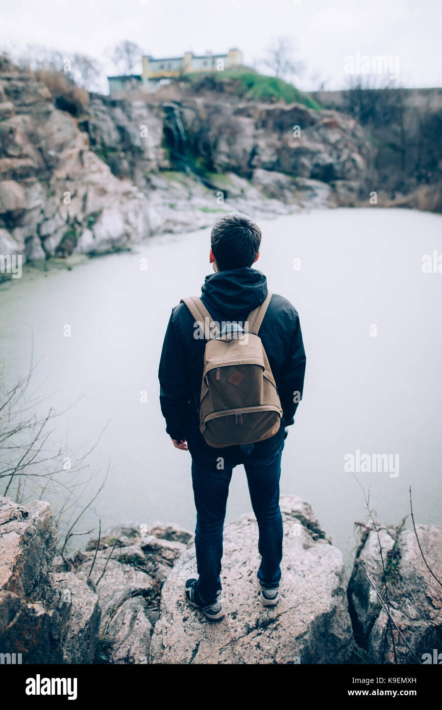 Back view of handsome man standing on rocky cliff and enjoying nature ...