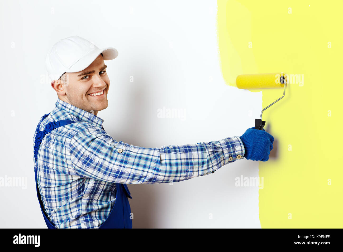 Happy young male painter painting a wall Stock Photo - Alamy
