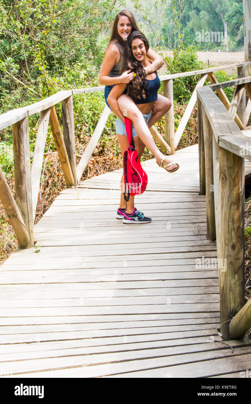 Two beautiful women hiking in nature on a wooden road Stock Photo - Alamy
