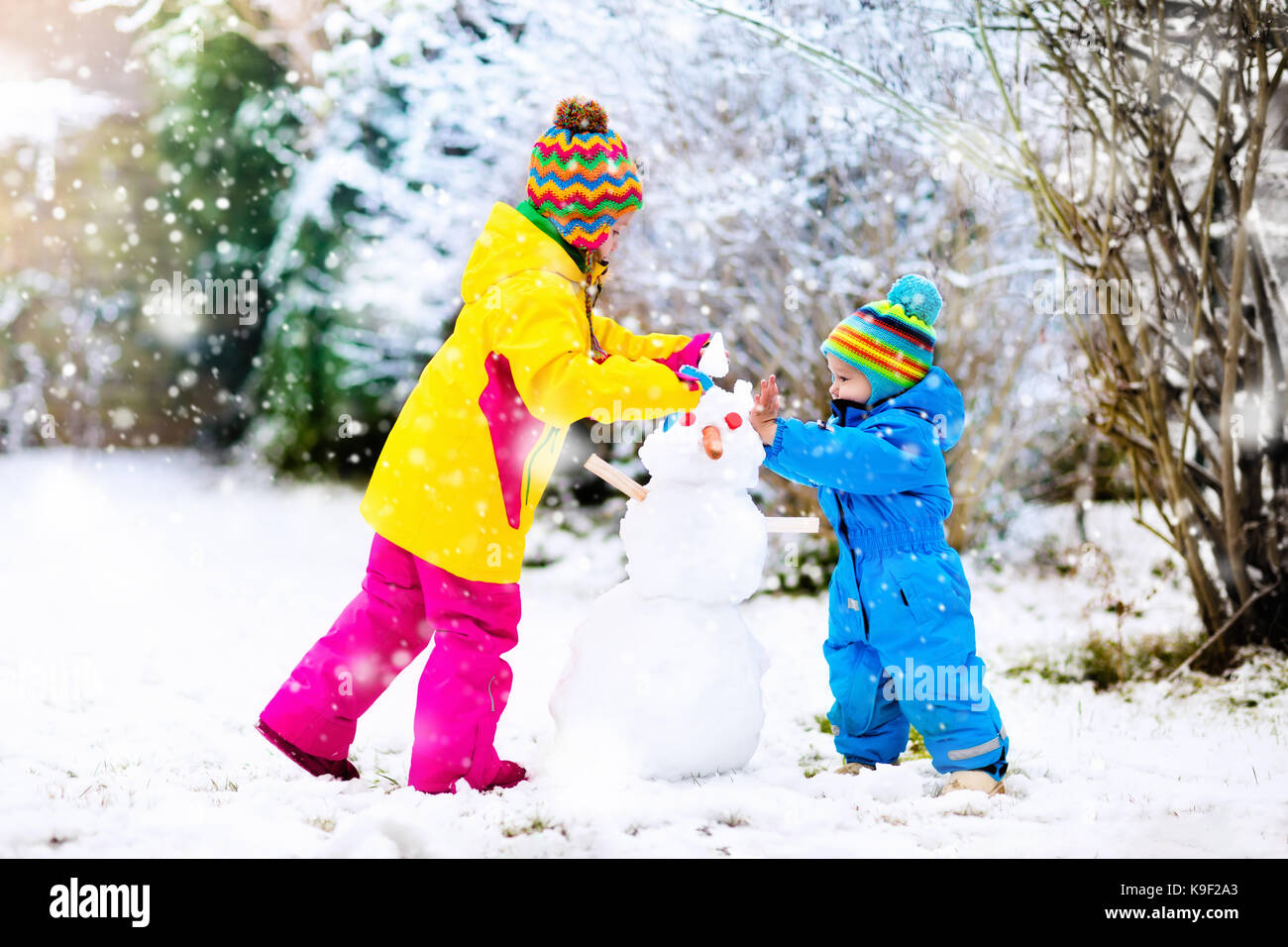 Children build snowman. Kids building snow man playing outdoors on ...