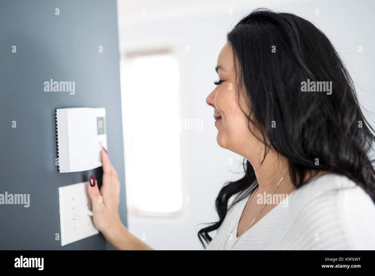 A Woman programming the temperature inside home Stock Photo - Alamy