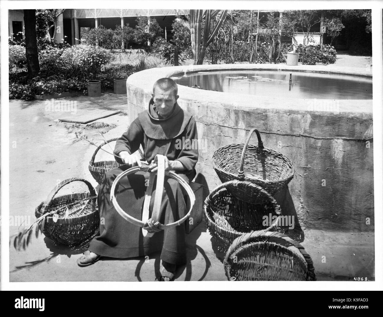 Monk sitting making baskets near the fountain in the garden at Mission ...
