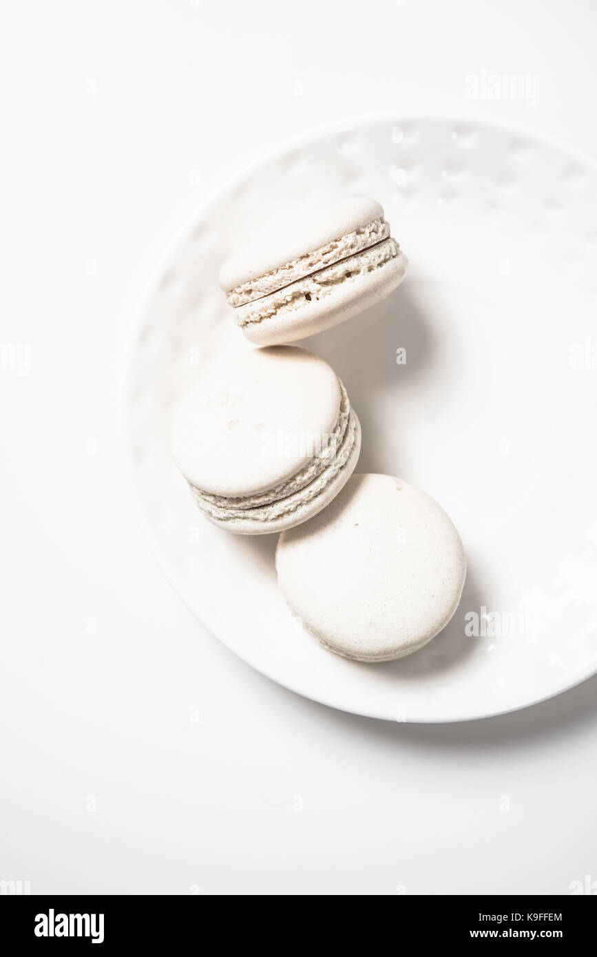 Three beige white macaroon cookies on plate on white background ...
