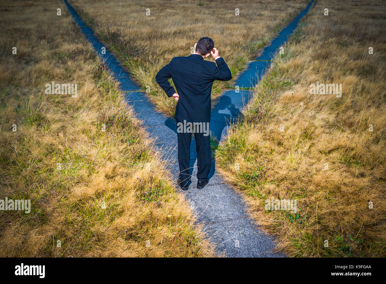 A man in a business suit stands at a cross road trying to figure out ...