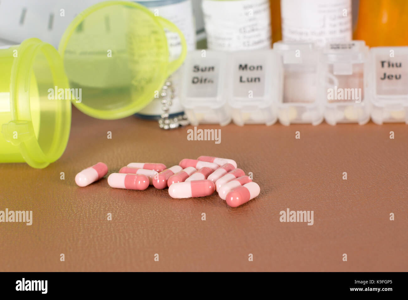 tiny pink pills with medication bottles and containers in background ...
