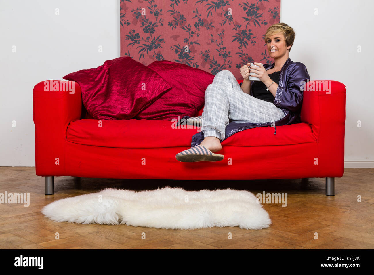 A woman on a sofa cuddling a cushion Stock Photo - Alamy