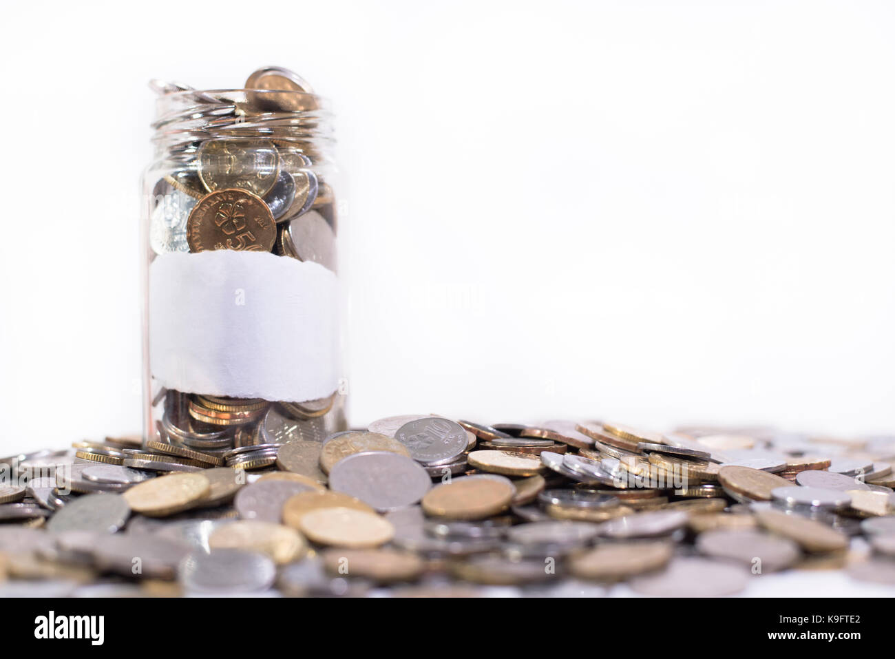 Glass jar filled with coins on a group of coins. attached with empty ...