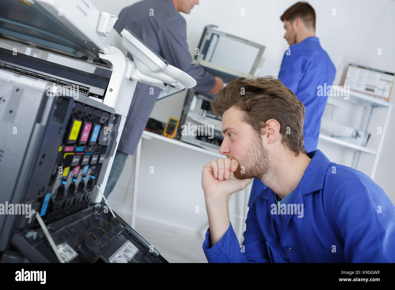 young efficient engineer working on a printer and adjusting components ...