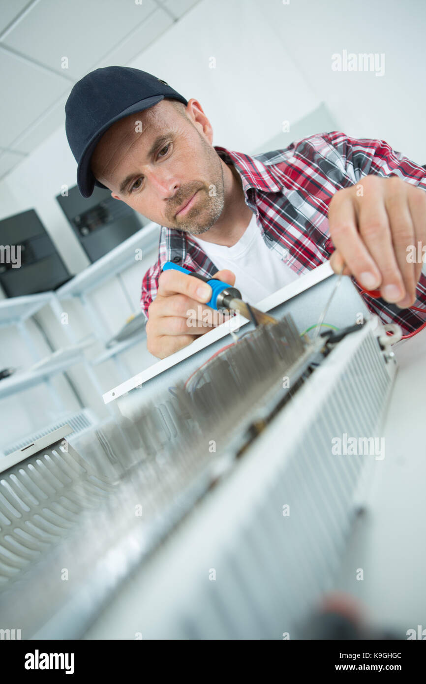 male plumber repairing radiator with a soldering iron Stock Photo - Alamy