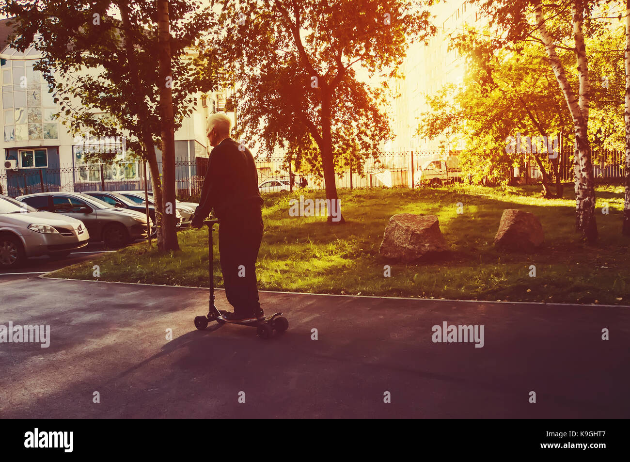 Old gray-haired grandfather, riding her scooter in the Park in sunlight ...