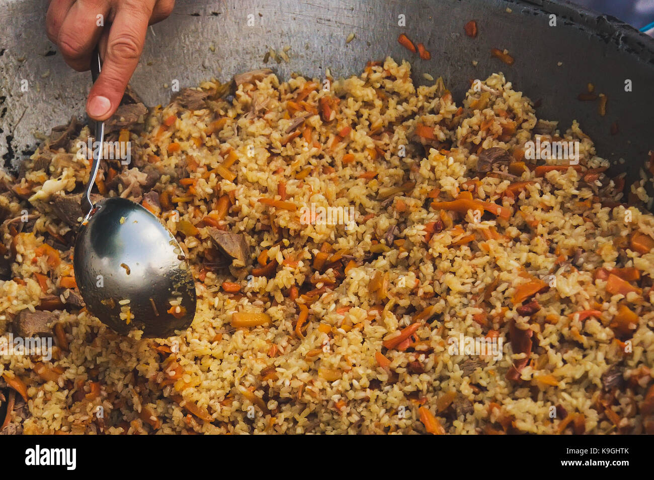 Ladle in kazane with Uzbek pilaf. Steamed rice with meat. The Asian ...