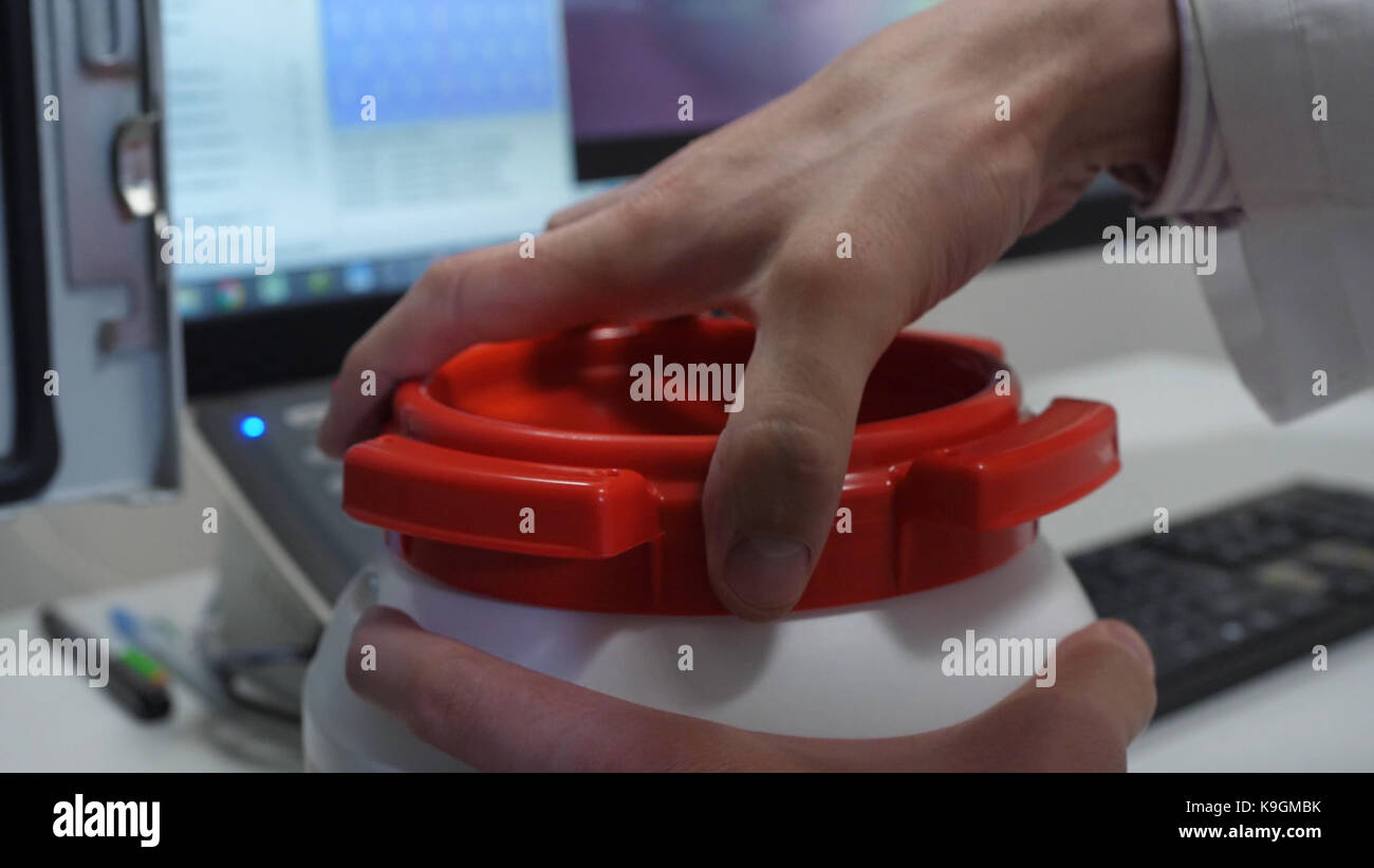 Chemical scientist opening white unlabeled plastic tank canister with ...