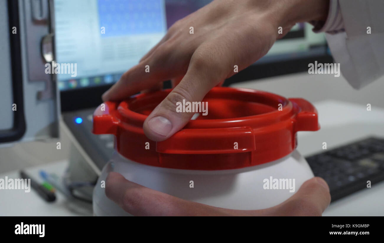Chemical scientist opening white unlabeled plastic tank canister with ...