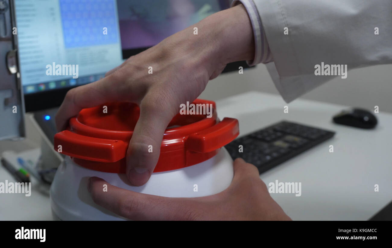 Chemical scientist opening white unlabeled plastic tank canister with ...