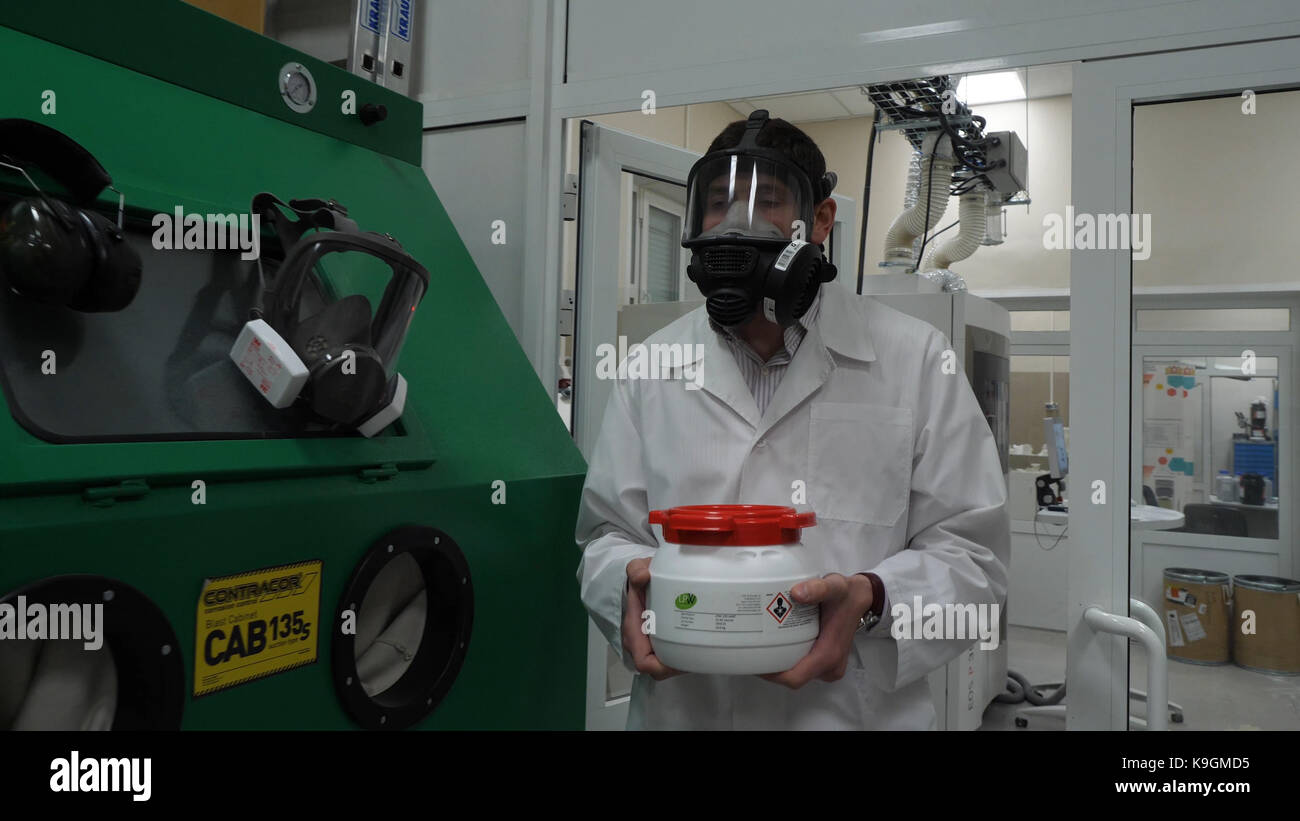 Scientist wearing protective suit and carrying a jar of toxic liquid ...