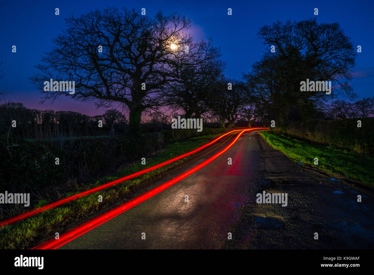 Moonlit Country road with light trail Stock Photo - Alamy