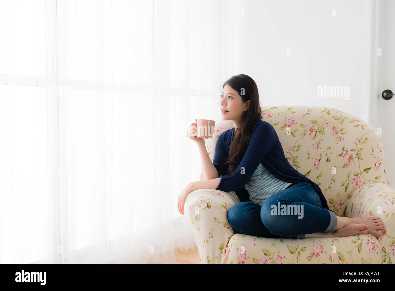 sweet calm female student holding cup drinking hot coffee and looking ...