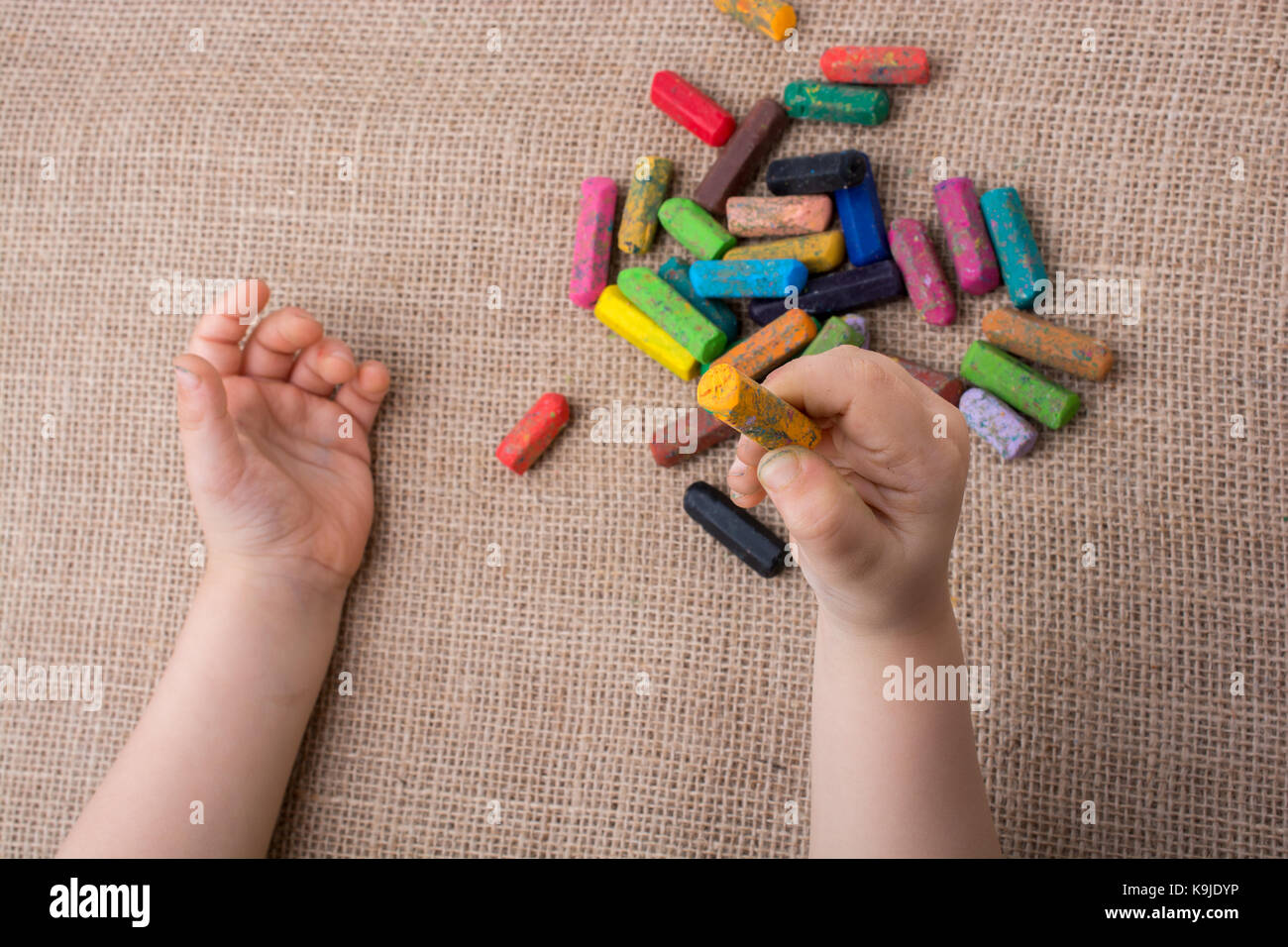 Used color crayons and a toddlers hand holding one Stock Photo - Alamy
