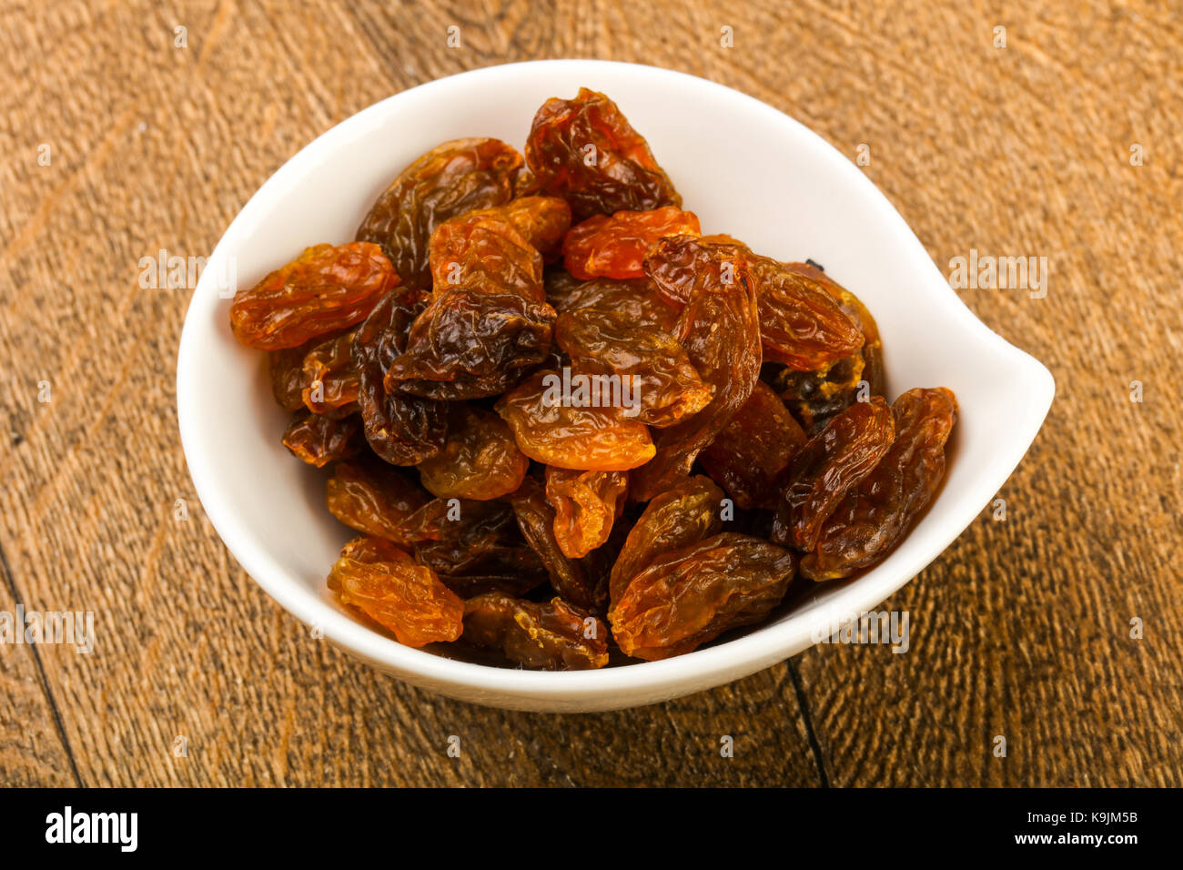 Dry Raisin in the bowl over the wooden background Stock Photo - Alamy