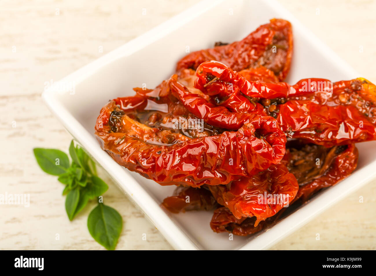 Dried tomato in olive oil with basil leaves Stock Photo - Alamy
