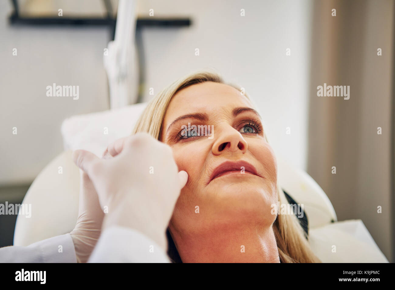 Closeup of a doctor administering botox injections around the eyes of a ...