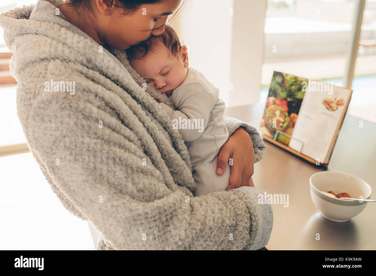 Close up of woman with child in kitchen at home. newborn baby boy ...