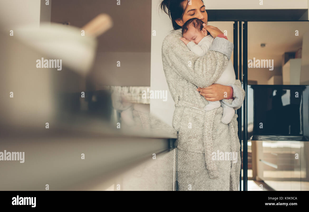 Caring young woman with her newborn baby boy sleeping in her arms in ...