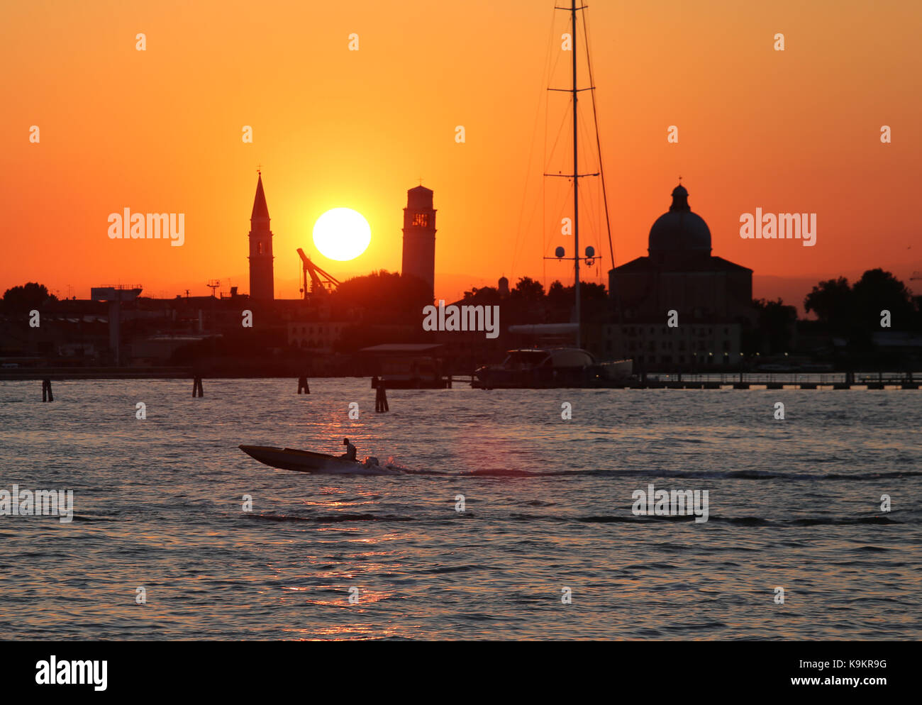 sun at sunset in VENICE in Italy and the shape of the churches and bell ...