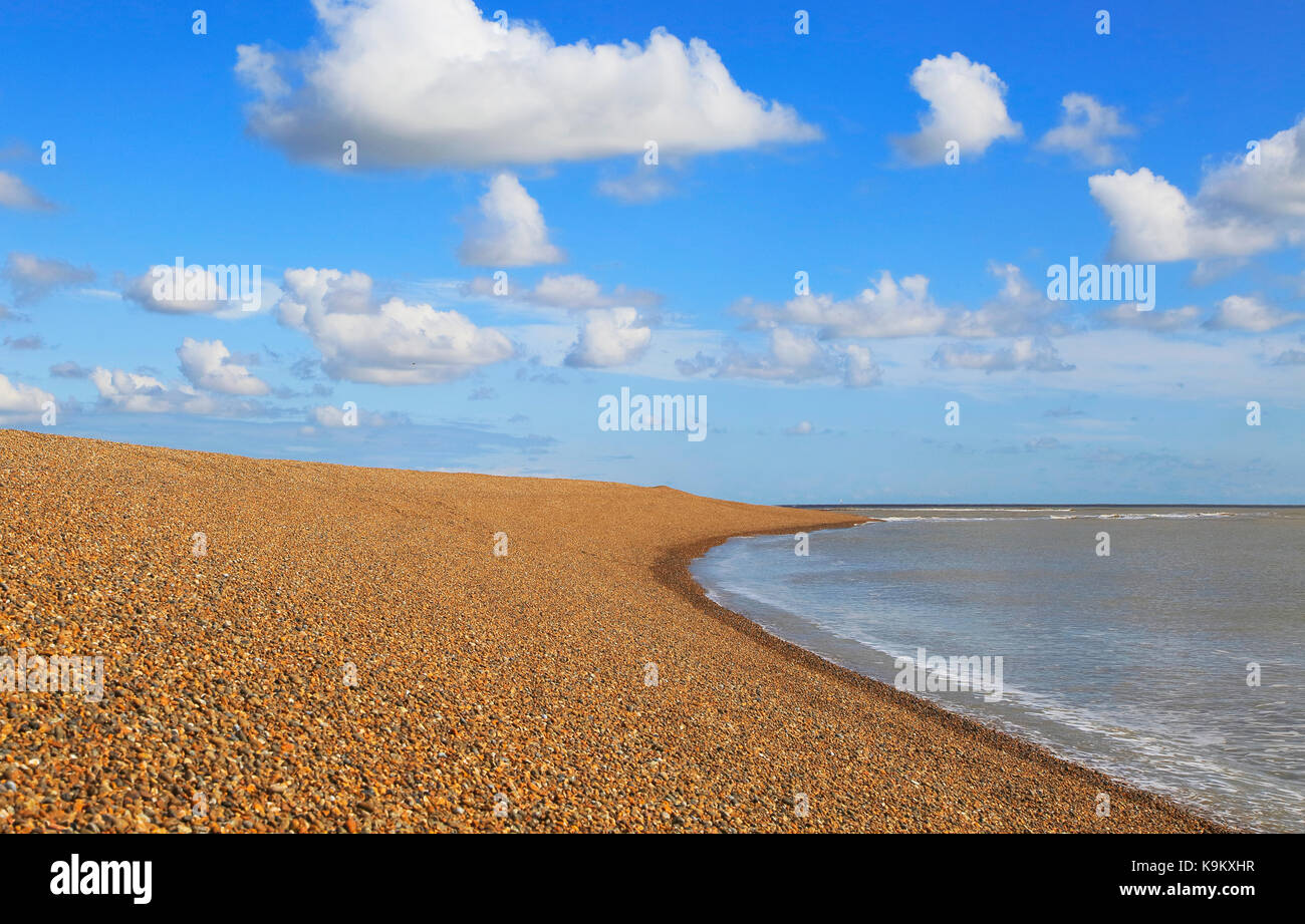 Steep beach profile sediment calm water blue sky white clouds landscape ...