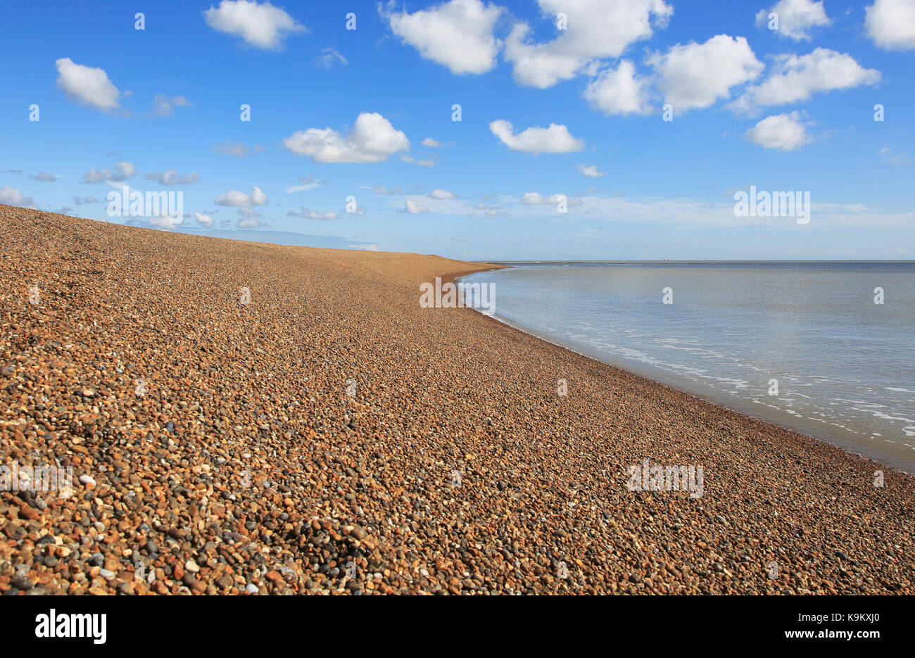 Steep beach profile sediment calm water blue sky white clouds landscape ...