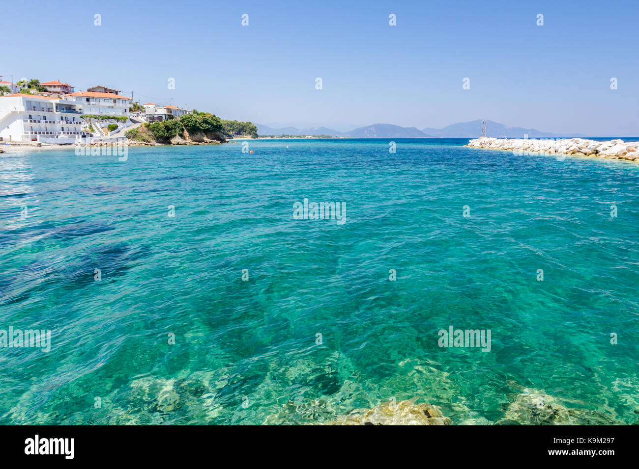 Rocky shallows with crystal clear water and beautiful settlement over ...