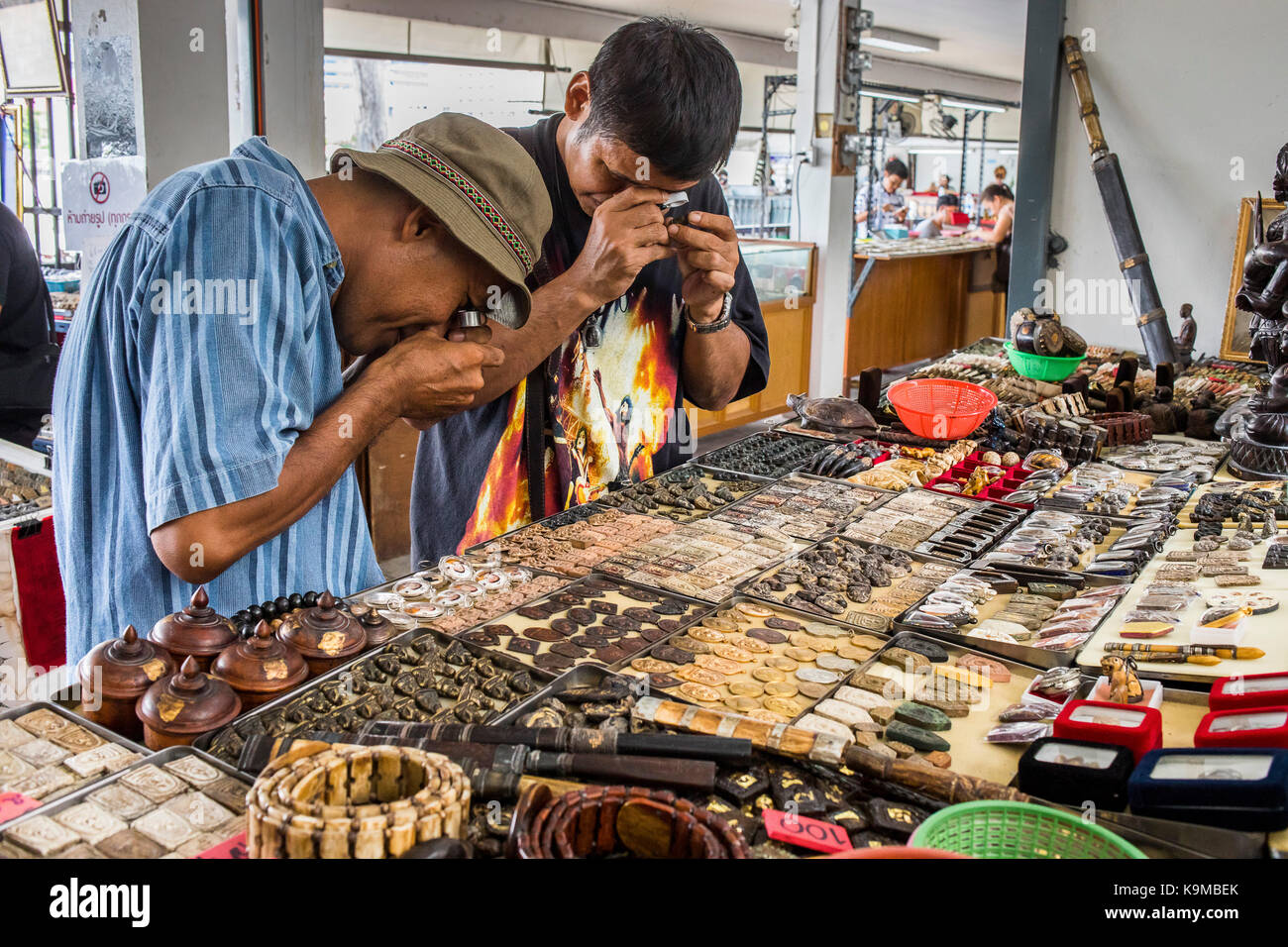 Collectors with magnifying glass searching small Buddhist amulets ...