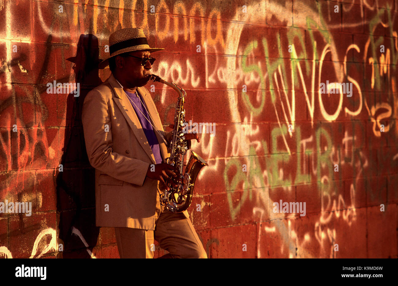 A Jazz Musician Playing on a City Street in Front of a Graffiti Covered ...