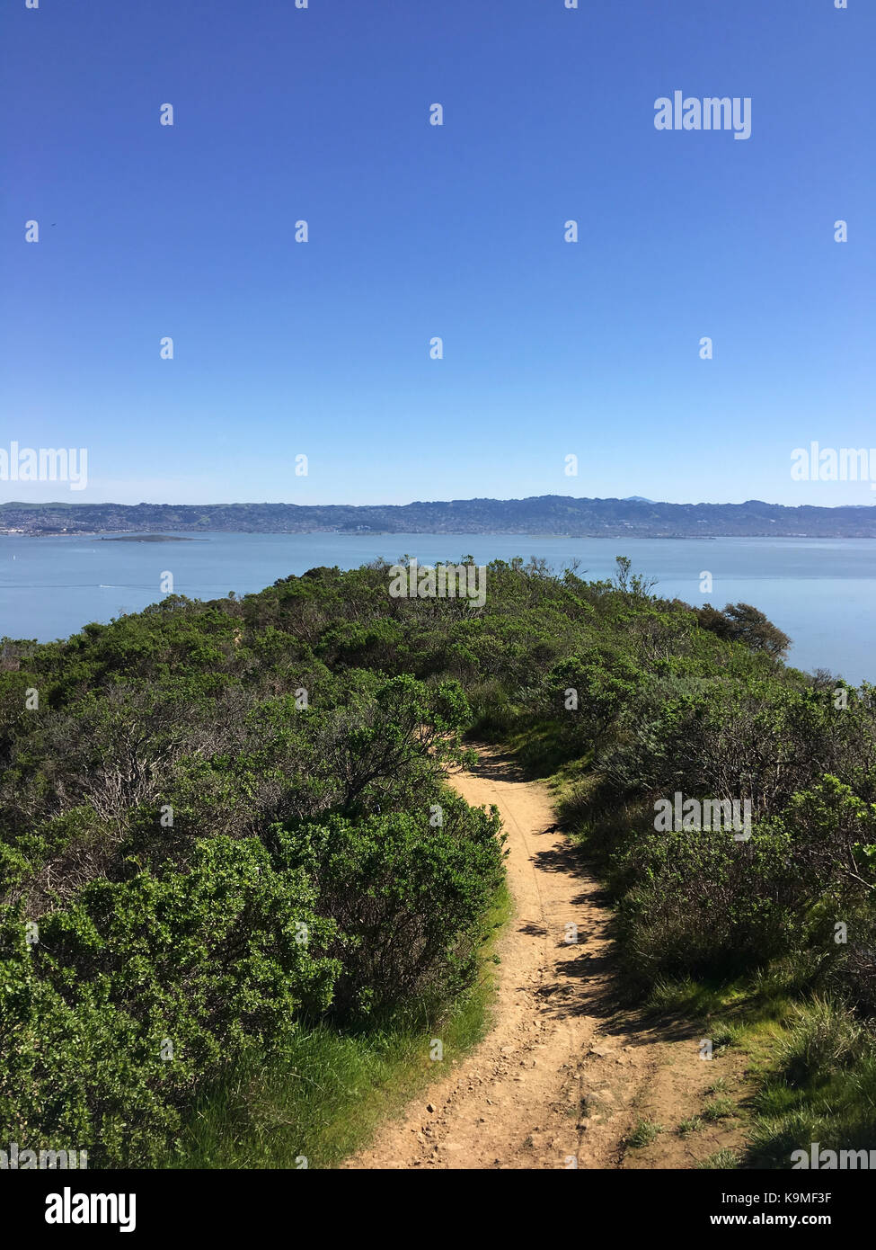 Trail on top of a hill overlooking blue water in a bay with perfect ...
