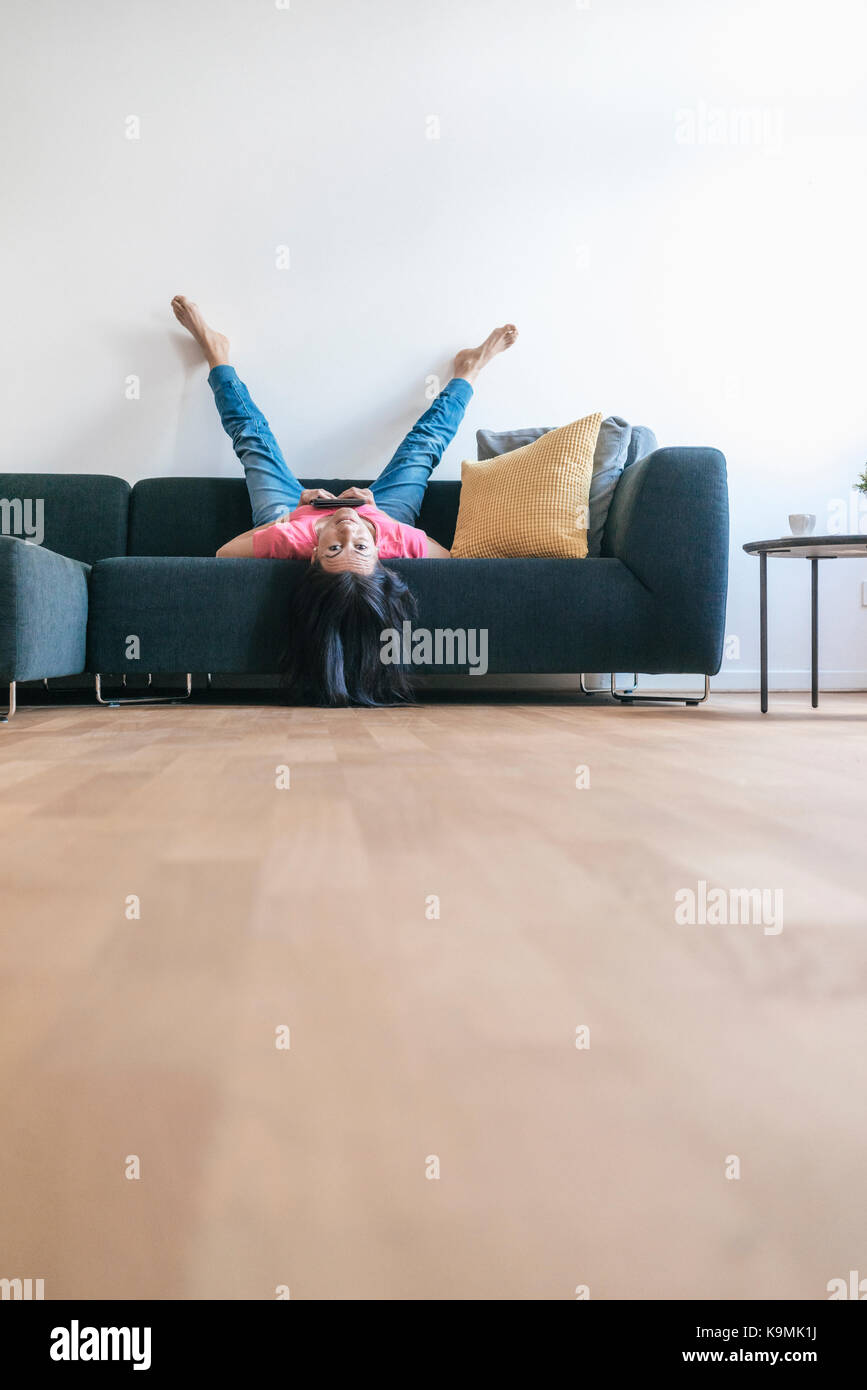 Woman at home lying on sofa upside down Stock Photo - Alamy