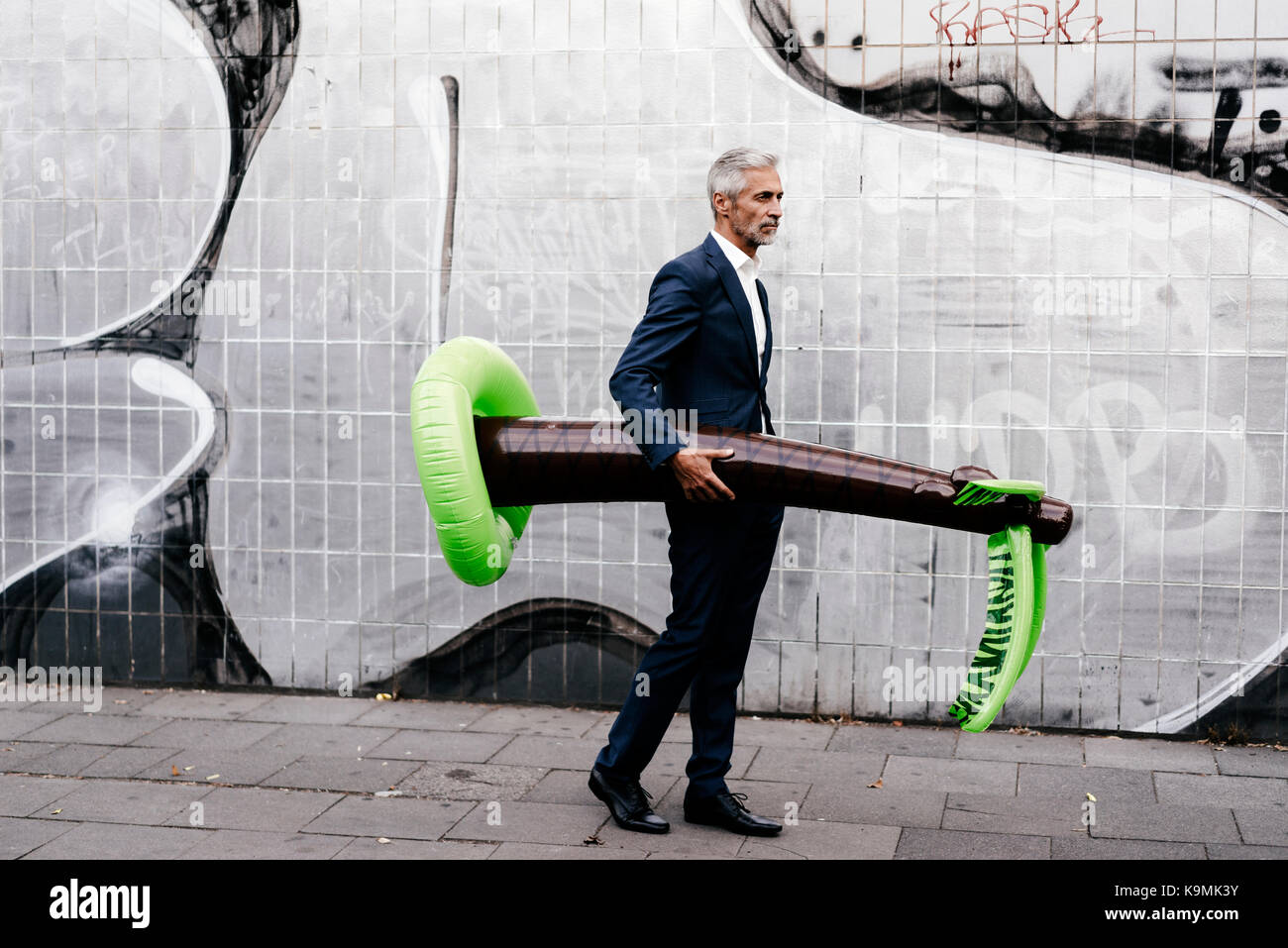 Mature businessman outdoors with inflatable palm tree Stock Photo - Alamy