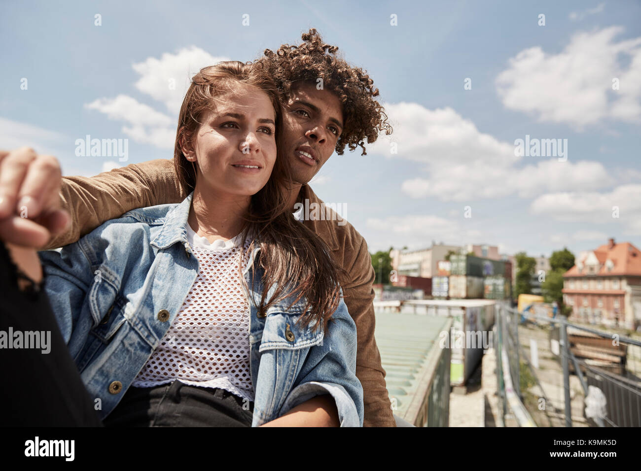 Young couple sitting on a wall Stock Photo - Alamy