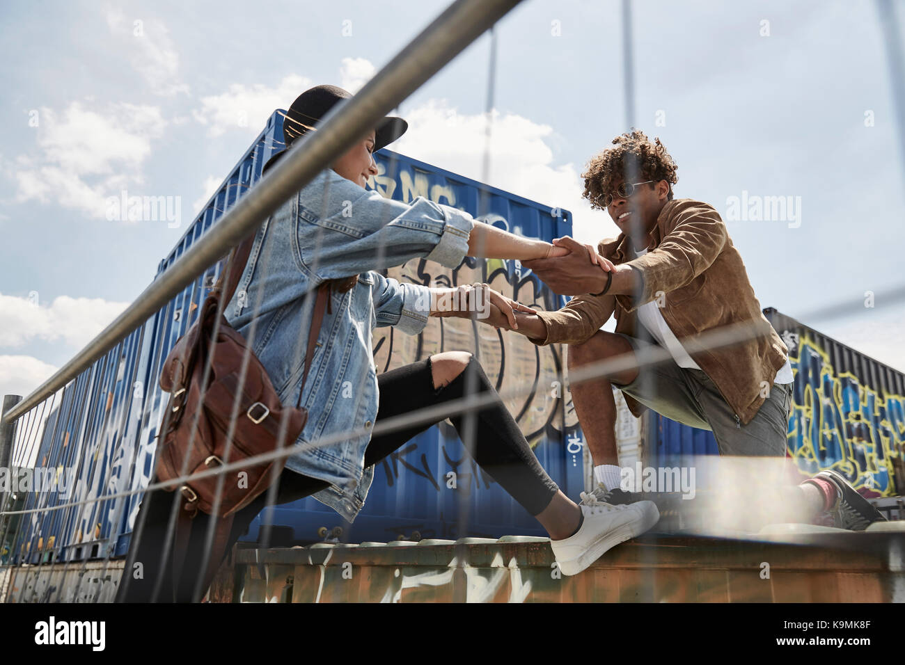 Young couple climbing over wall Stock Photo - Alamy