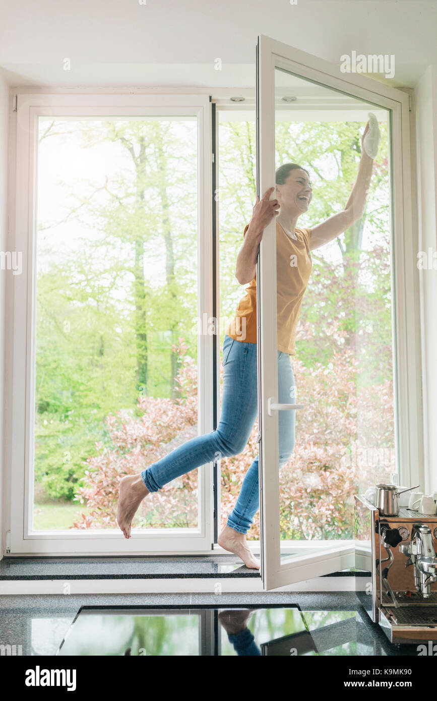 Happy woman standing on windowsill cleaning the window Stock Photo - Alamy