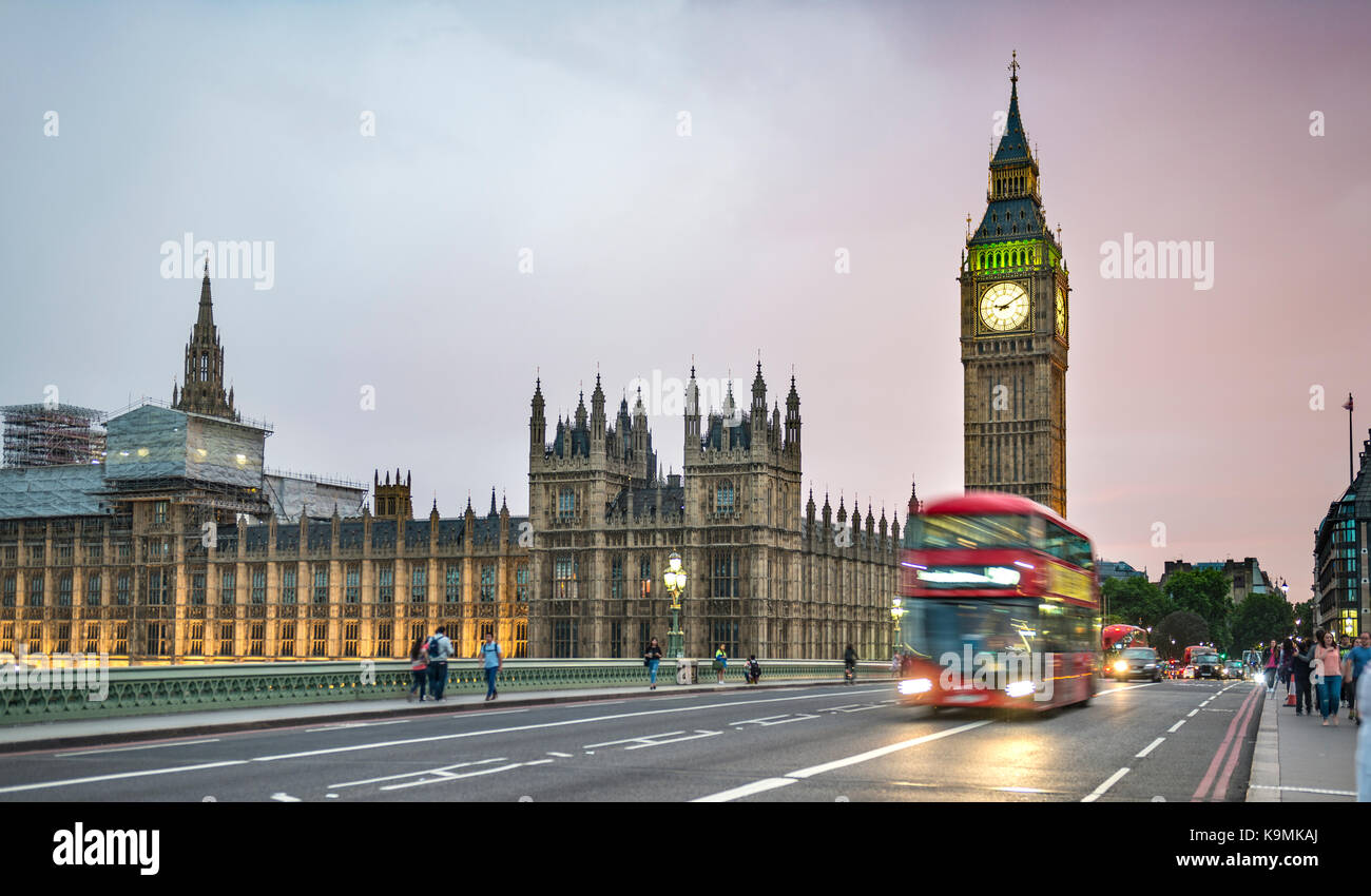 Red double-decker bus on the Westminster Bridge, evening twilight, Palace of Westminster and Big ...