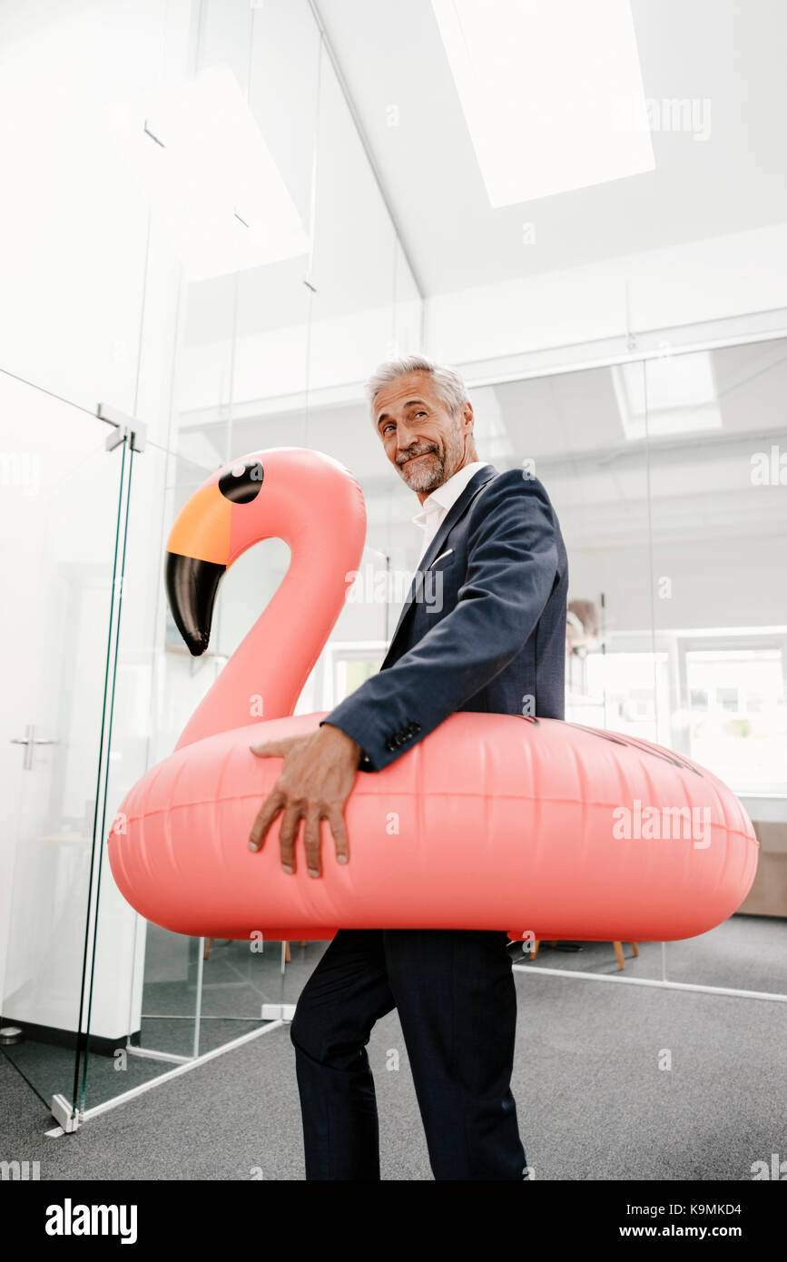 Businessman in office with inflatable flamingo Stock Photo - Alamy