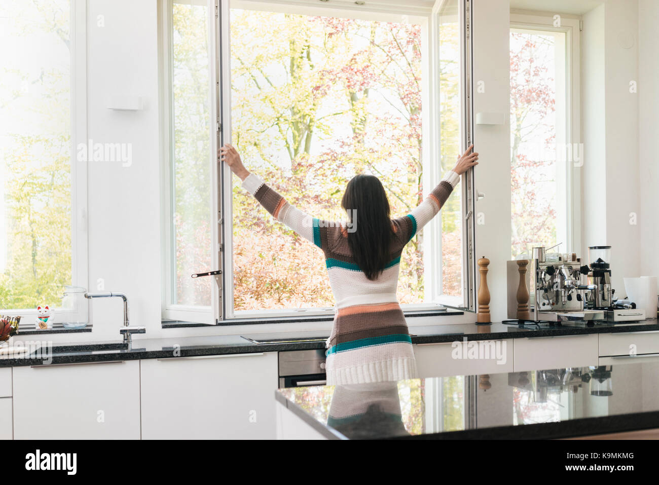 Woman in kitchen opening the window Stock Photo - Alamy