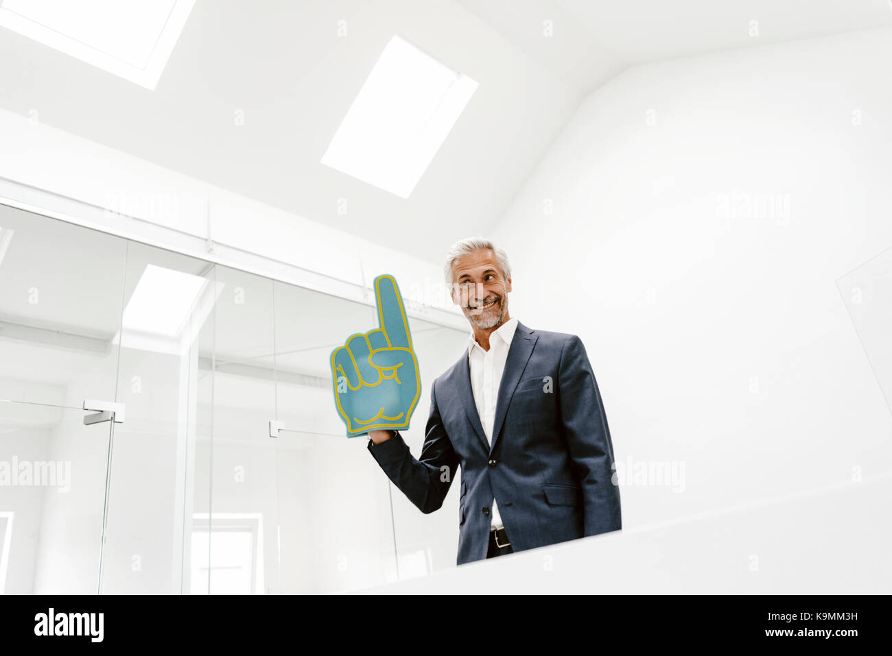 Smiling mature businessman holding toy hand in office Stock Photo - Alamy