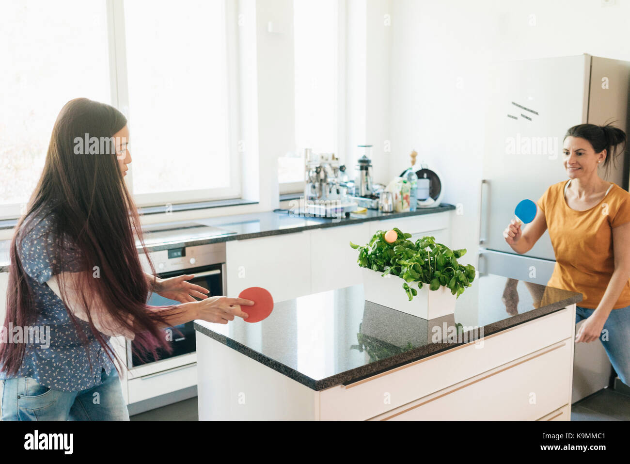 Two women playing table tennis on kitchen counter Stock Photo - Alamy
