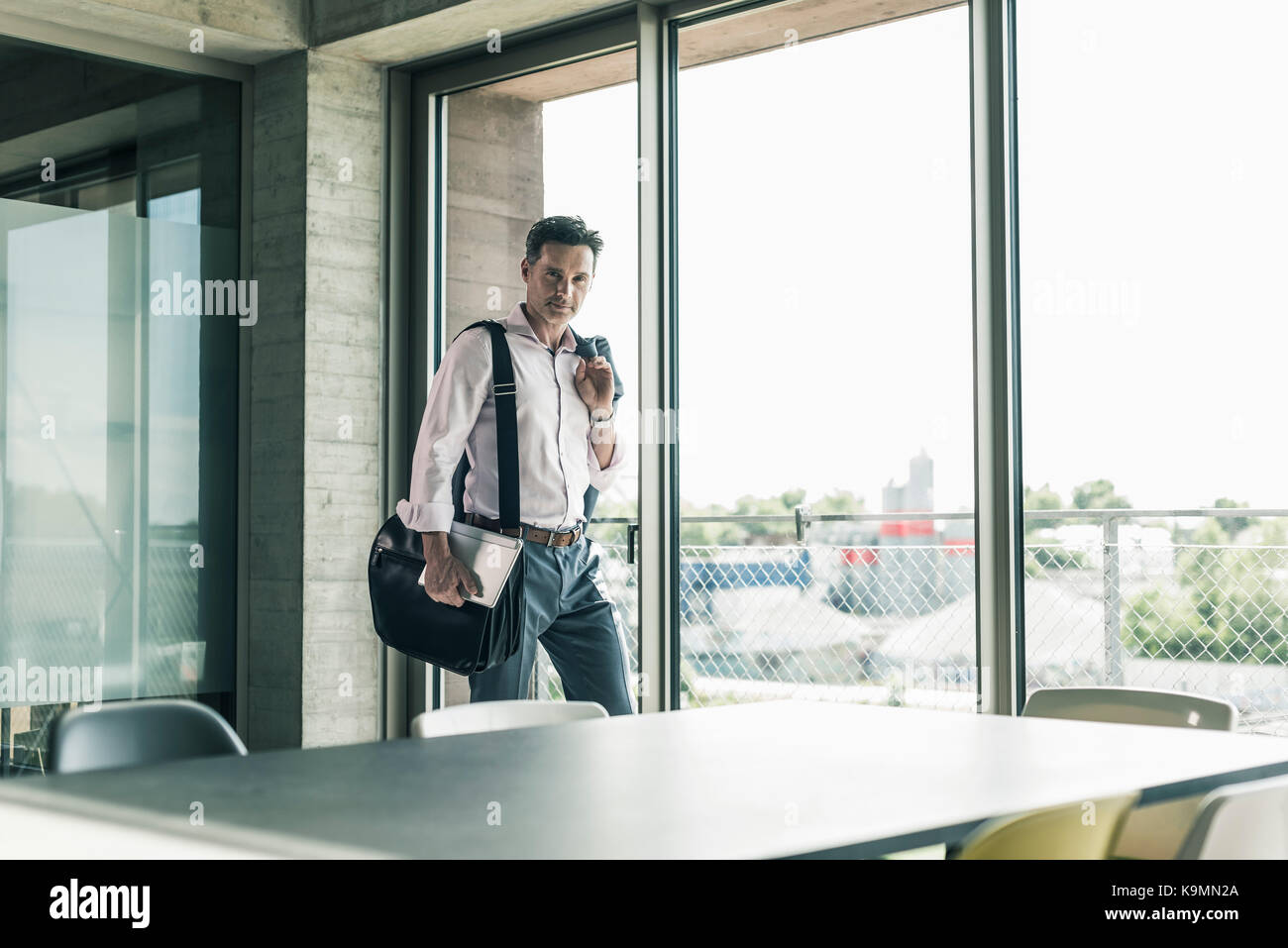 Businessman standing by window, entering the office Stock Photo - Alamy